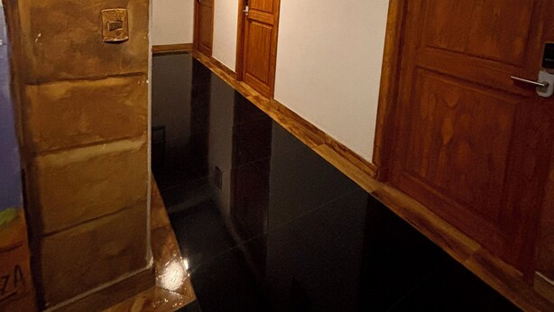 Um corredor com portas de madeira, uma placa indicando 'PISO 5' e chão de azulejos.