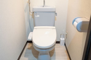Sanitário moderno com painel de controle, função bidê e mangueira bidet acoplada à parede.