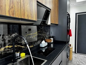 Uma cozinha moderna com bancada preta, pia de aço inoxidável e armários de madeira.