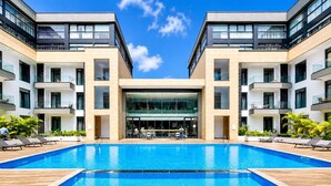 Um hotel moderno com piscina central, várias varandas e fachada de vidro.
