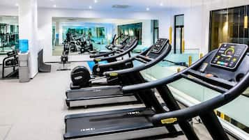 Academia com esteiras, aparelhos de musculação e um espelho grande.
