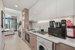 Uma cozinha moderna com forno embutido, micro-ondas e máquina de café, pia e extintor de incêndio.
