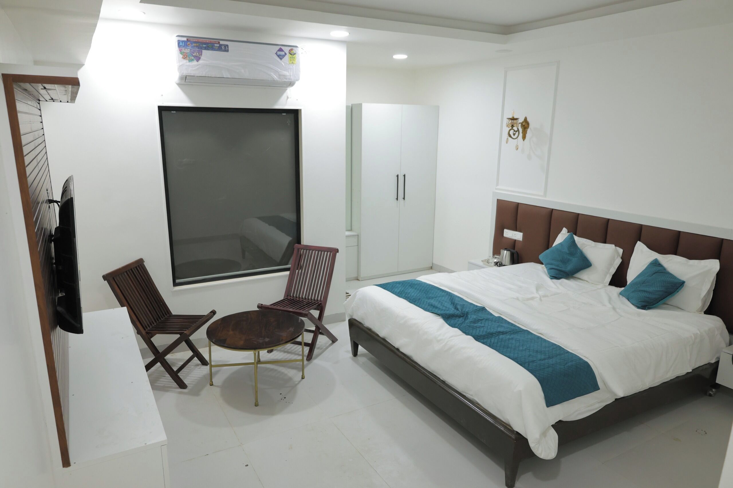 Quarto de hotel com cama, escrivaninha, cadeira, janela e guarda-roupa.