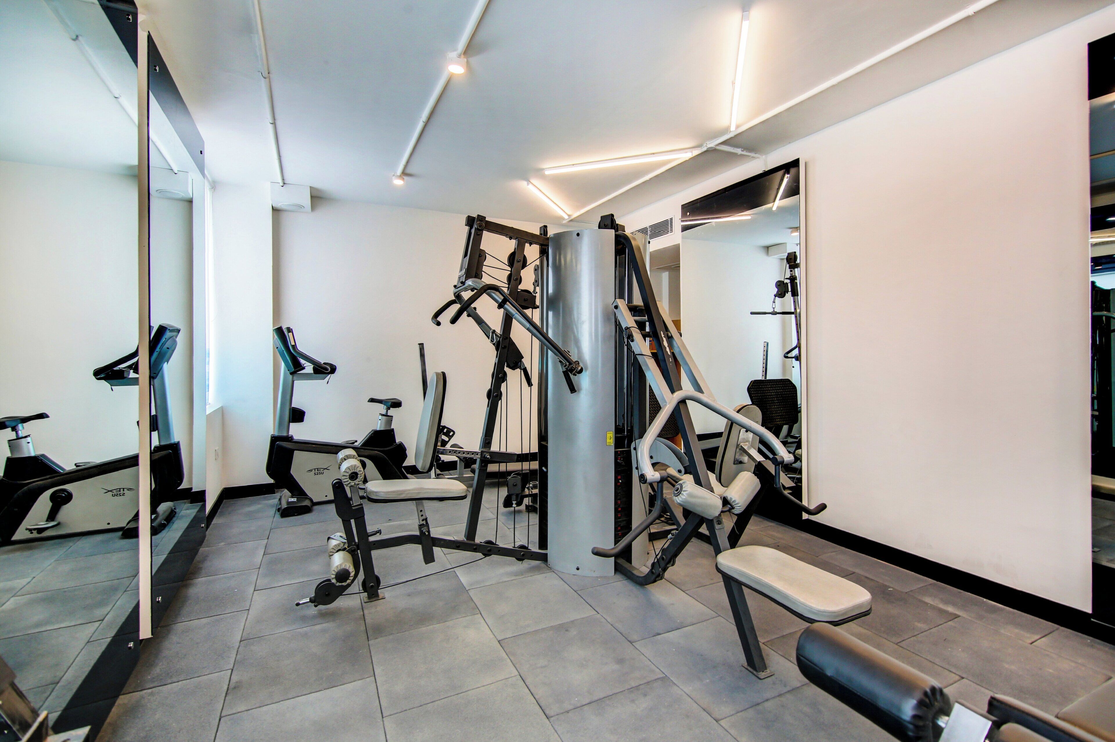 Uma academia com diversos equipamentos de exercício, incluindo esteira, bicicleta ergométrica e aparelhos de musculação.