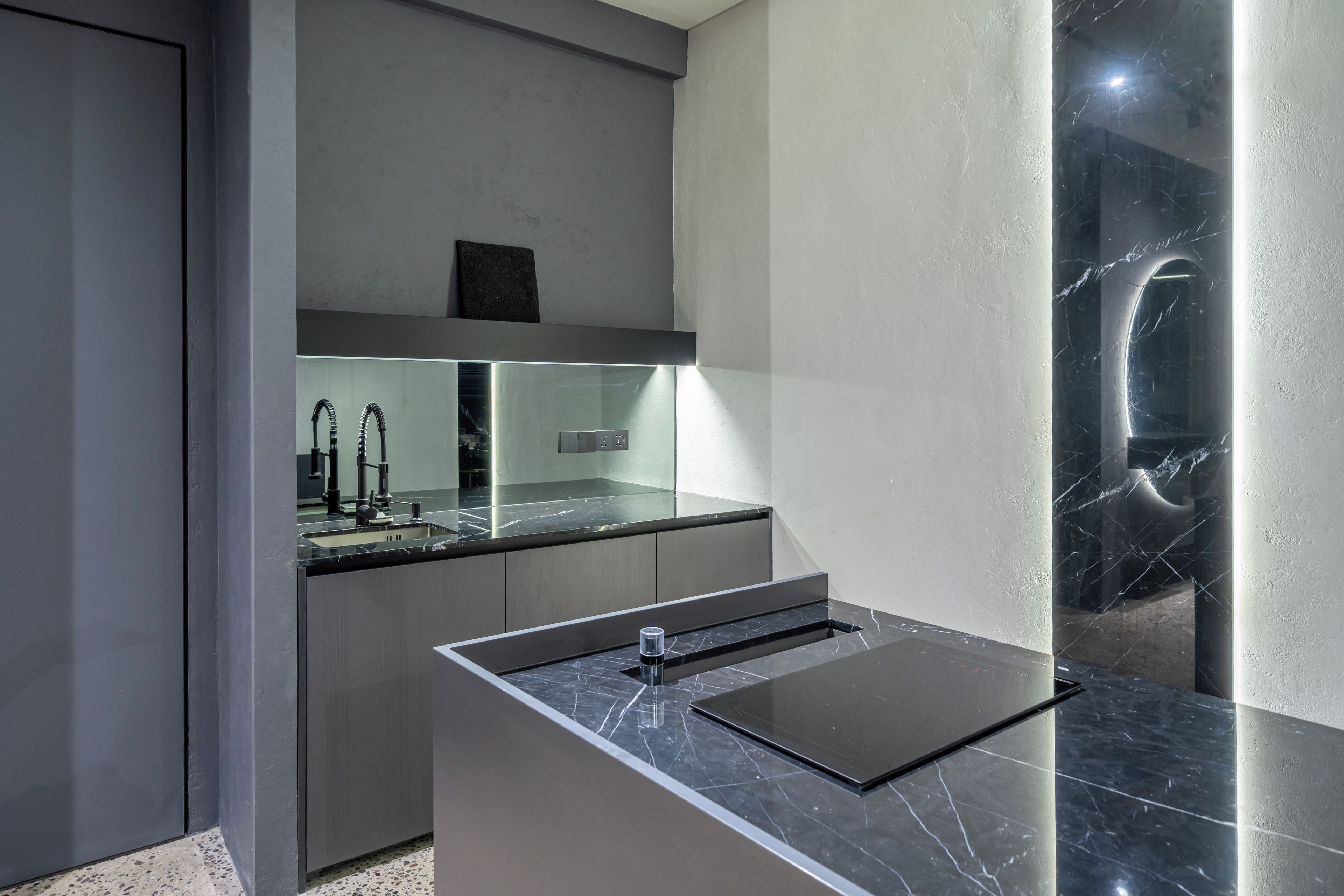 Cozinha moderna com bancada de mármore preto, eletrodomésticos de aço inoxidável e uma grande janela.