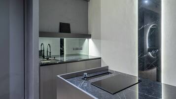 Cozinha moderna com bancada de mármore preto, eletrodomésticos de aço inoxidável e uma grande janela.