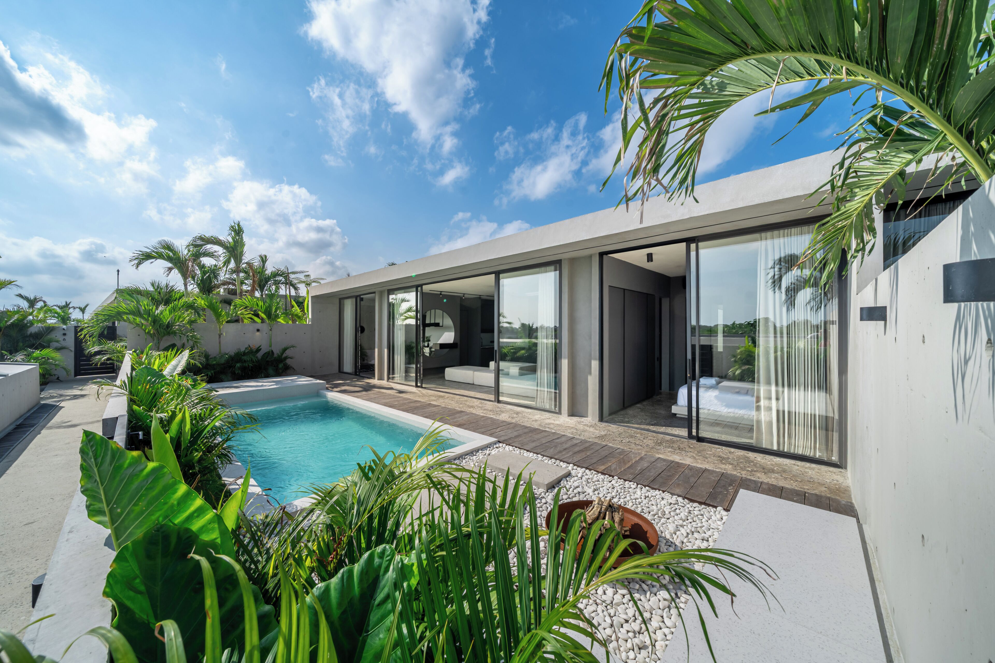 Uma casa moderna com piscina, janelas amplas e plantas tropicais.
