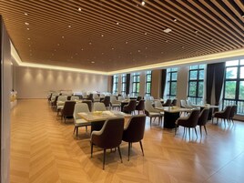 Uma sala de conferências com design moderno no teto, grandes janelas e um padrão de piso em espinha de peixe.
