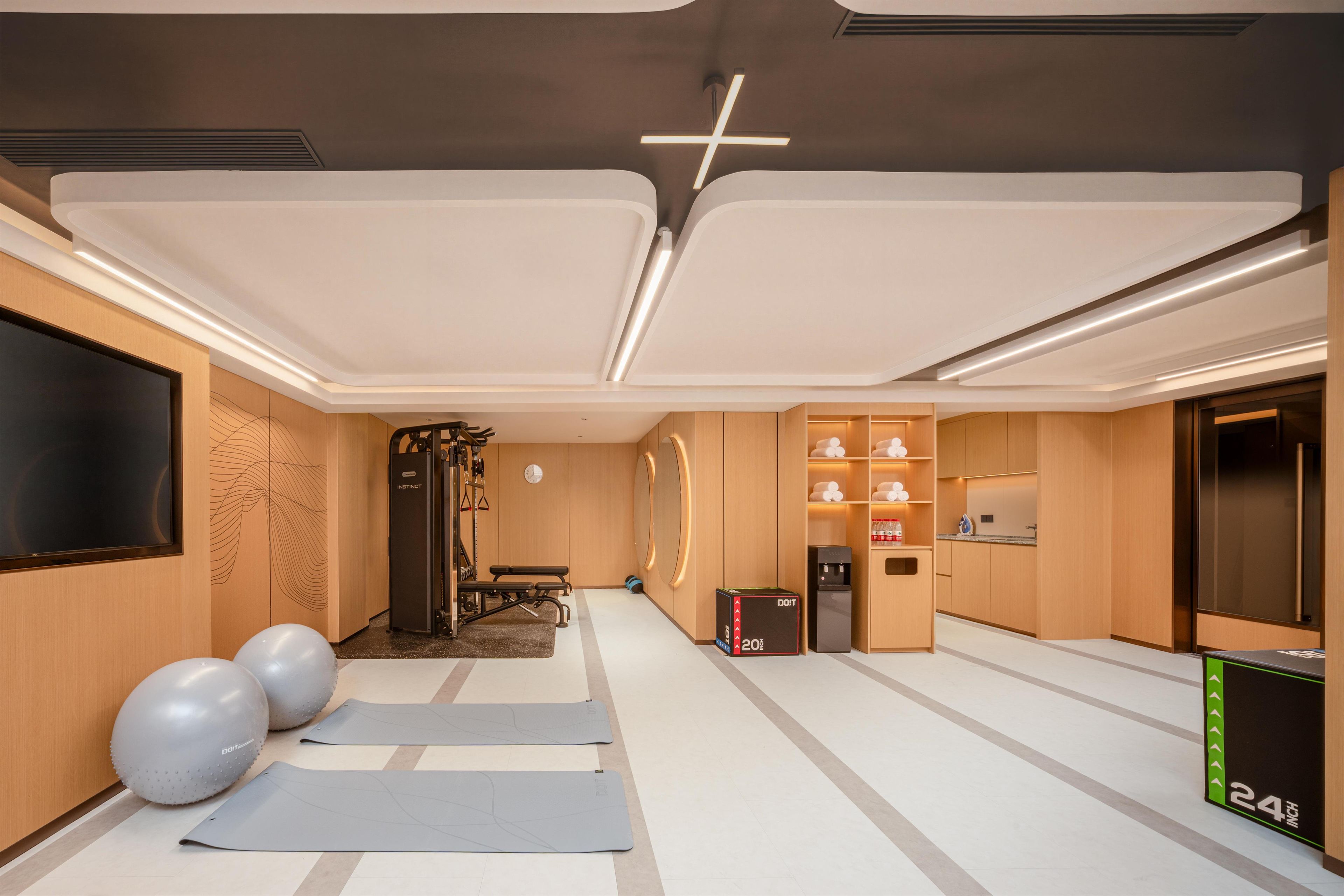Uma academia moderna com equipamentos de ginástica, tapetes de yoga e um bebedouro.