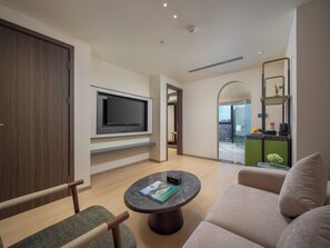Sala de estar moderna com televisão de tela plana na parede, mesa de centro redonda com livros, sofá e vista da cidade através de uma porta de vidro.