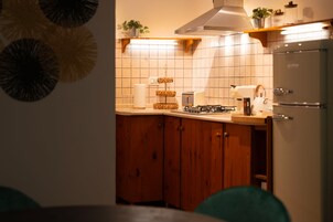 Uma cozinha com armários de madeira, fogão a gás, geladeira branca e uma cesta suspensa com uma planta.