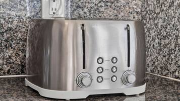 Uma torradeira de aço inoxidável com várias configurações sobre uma bancada de granito.