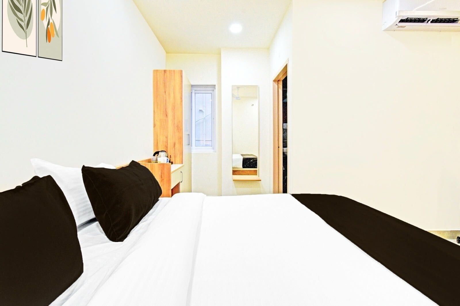 Quarto de hotel com cama, mesa de cabeceira, espelho e janela.
