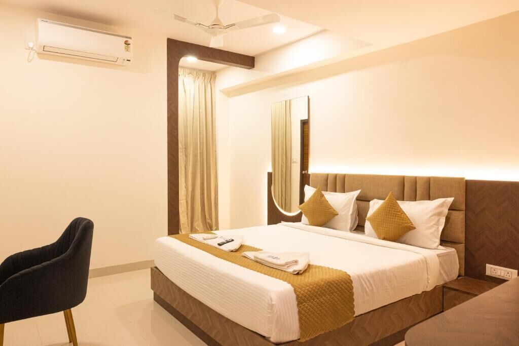 Quarto de hotel com cama, cadeira, ar condicionado e ventoinha de teto.