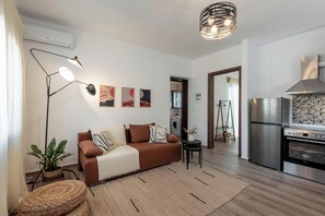 Uma sala de estar moderna com um sofá, uma luminária de chão e obras de arte na parede.