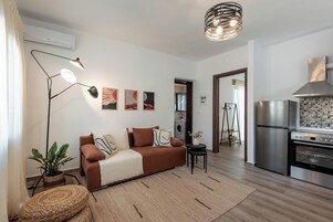 Uma sala de estar moderna com um sofá, uma luminária de chão e obras de arte na parede.