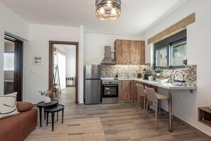 Uma cozinha moderna com forno embutido, geladeira e armário de madeira. Há uma área de jantar com mesa e cadeiras.