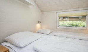 Quarto com duas camas, janela com vista para o verde e luminária na parede.