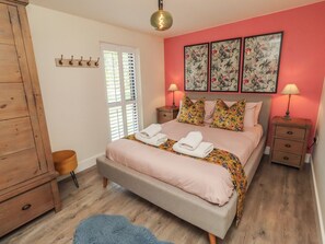 Quarto com cama, mesas de cabeceira, guarda-roupa e janela com persianas.