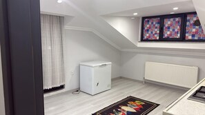 Quarto compacto com radiador branco, eletrodoméstico pequeno e tapete colorido.