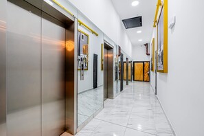 Corredor moderno com elevadores e piso de mármore polido.