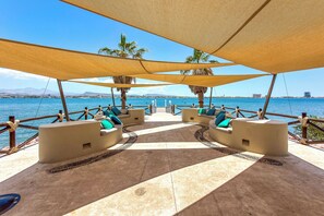 Uma área externa ensolarada com cadeiras de lounge e vista para o mar.