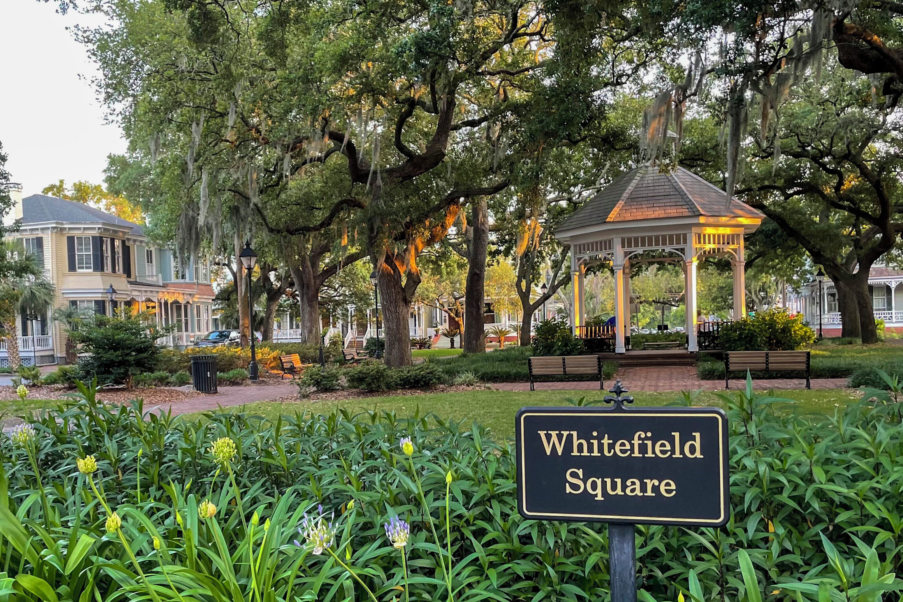 Um parque com um coreto, bancos e uma placa indicando 'Whitefield Square'.