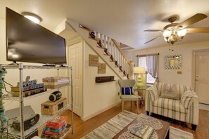Uma sala de estar com televisão, livros, rádio e mesa de centro.