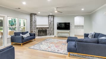Uma sala de estar com dois sofás, uma lareira, uma televisão e uma parede decorativa em pedra.