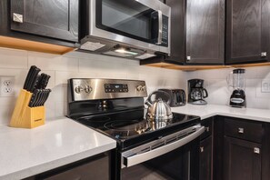 Uma cozinha moderna com eletrodomésticos de aço inoxidável, micro-ondas embutido e chaleira no fogão.