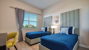 Quarto de hotel com duas camas, uma escrivaninha e uma cadeira.