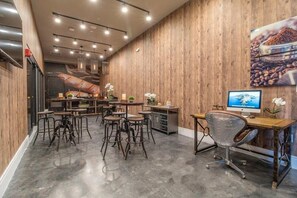 Interior de restaurante com paredes de madeira, várias mesas e cadeiras, uma mesa de escritório e uma televisão.