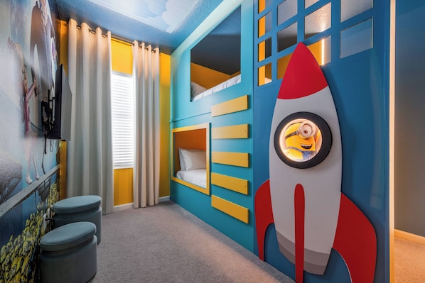 Quarto infantil com cama beliche, decoração de foguete na parede e janela com cortinas.