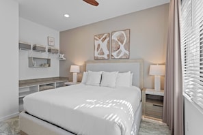 Quarto de hotel moderno com uma cama grande, duas mesas de cabeceira com abajures, cabeceira com arte abstrata, nichos e uma janela com persianas.