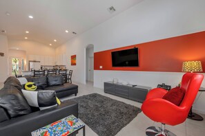 Uma sala de estar moderna com um sofá de couro preto, uma poltrona vermelha e um tapete cinzento.