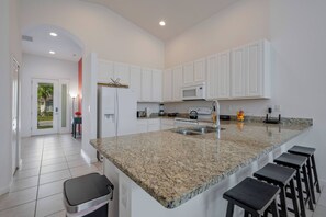 Cozinha moderna com armários brancos, bancada de granito e micro-ondas embutido.