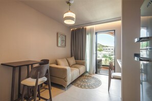 Uma sala de estar moderna com sofá, mesa de jantar, cadeiras, tapete estampado e luminária no teto.