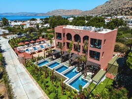 Um hotel com piscina no terraço, várias varandas e vista para o mar.