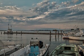 Uma marina com barcos atracados, um cais que se estende sobre a água e um céu nublado.