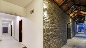 Um corredor com parede de pedra, portas de madeira e uma placa indicando os quartos 101 a 104.
