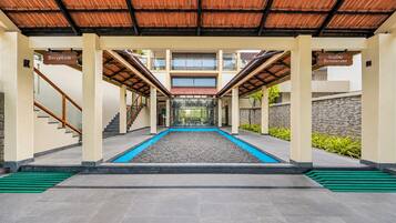 Uma área de recepção de hotel com piscina, balcão de atendimento e escada.