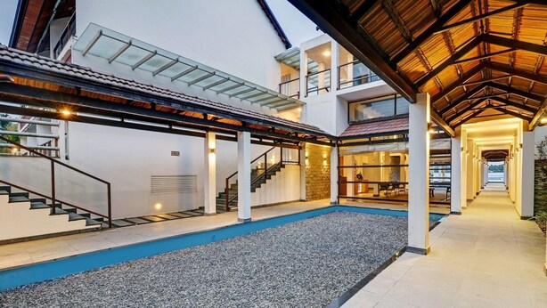 Um edifício moderno com área externa coberta, piscina e escada que leva a um andar superior.
