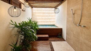 Uma área de spa com teto de madeira, hidromassagem e chuveiro.
