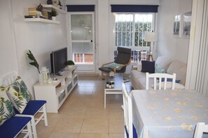 Uma sala compacta com televisão, área de estar e varanda com vista.