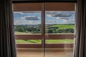 Uma varanda com vista para colinas verdes e um céu parcialmente nublado.