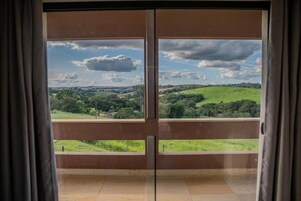 Uma varanda com vista para colinas verdes e um céu parcialmente nublado.