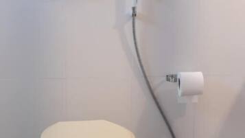 Um banheiro com vaso sanitário, bidê e lixeira.