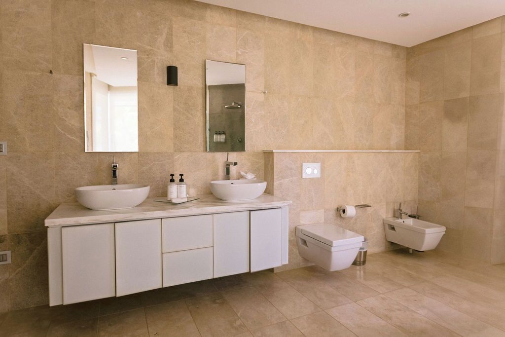Uma casa de banho moderna com duas pias, sanita e bidé.