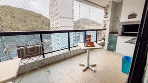 Varanda com mesa, cadeiras, varal e vista para prédios.