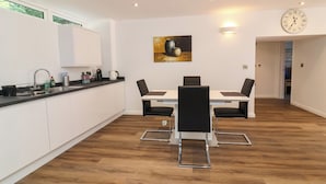 Uma cozinha moderna com armários brancos, bancada preta e um espaço de jantar com mesa e cadeiras.